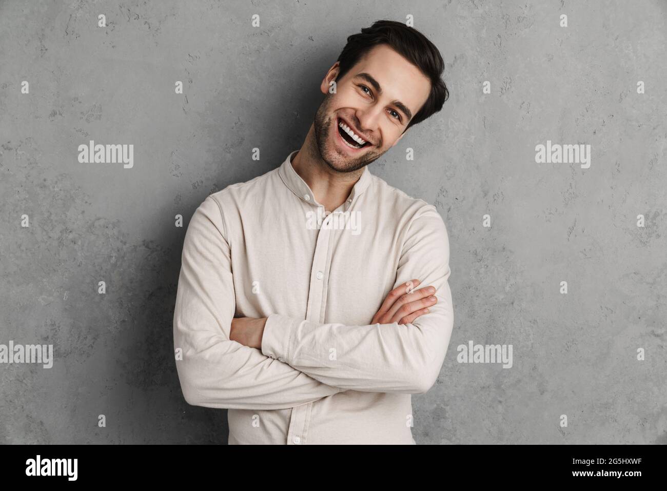 Joyful handsome guy smiling and looking at camera isolated over grey ...