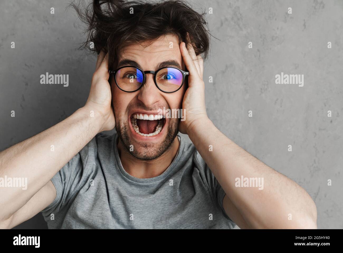 Irritated handsome guy screaming while grabbing his head isolated over ...