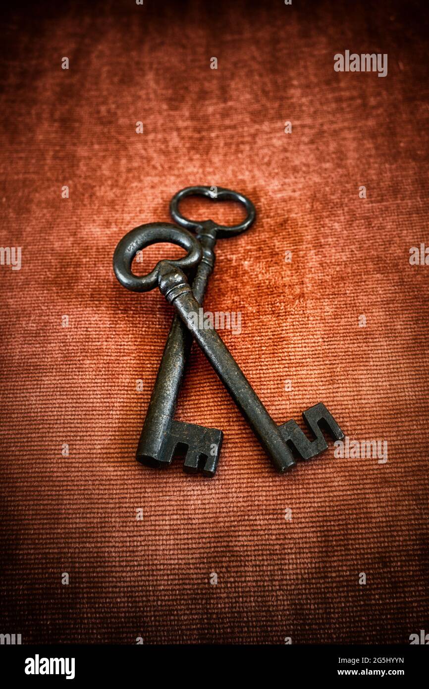 Old medieval wrought iron keys on red background Stock Photo - Alamy