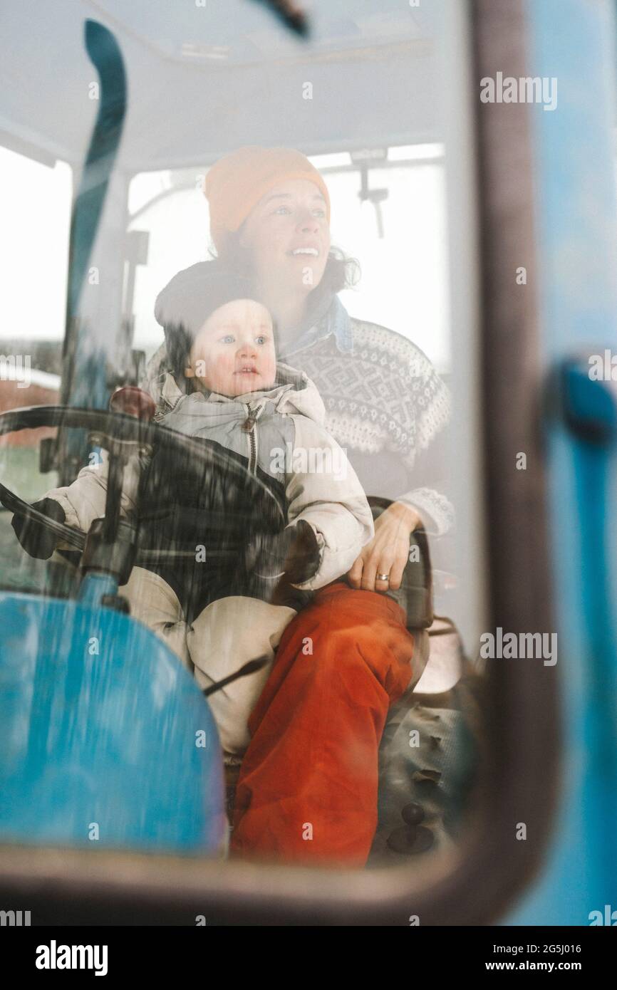 Mother and daughter sitting in tractor seen through windshield Stock ...