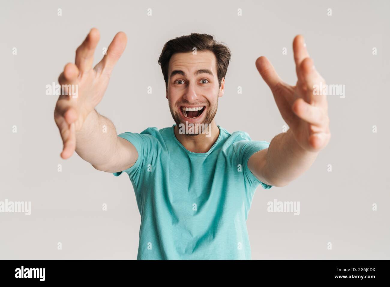 Joyful handsome guy smiling and reaching out hands to camera isolated ...