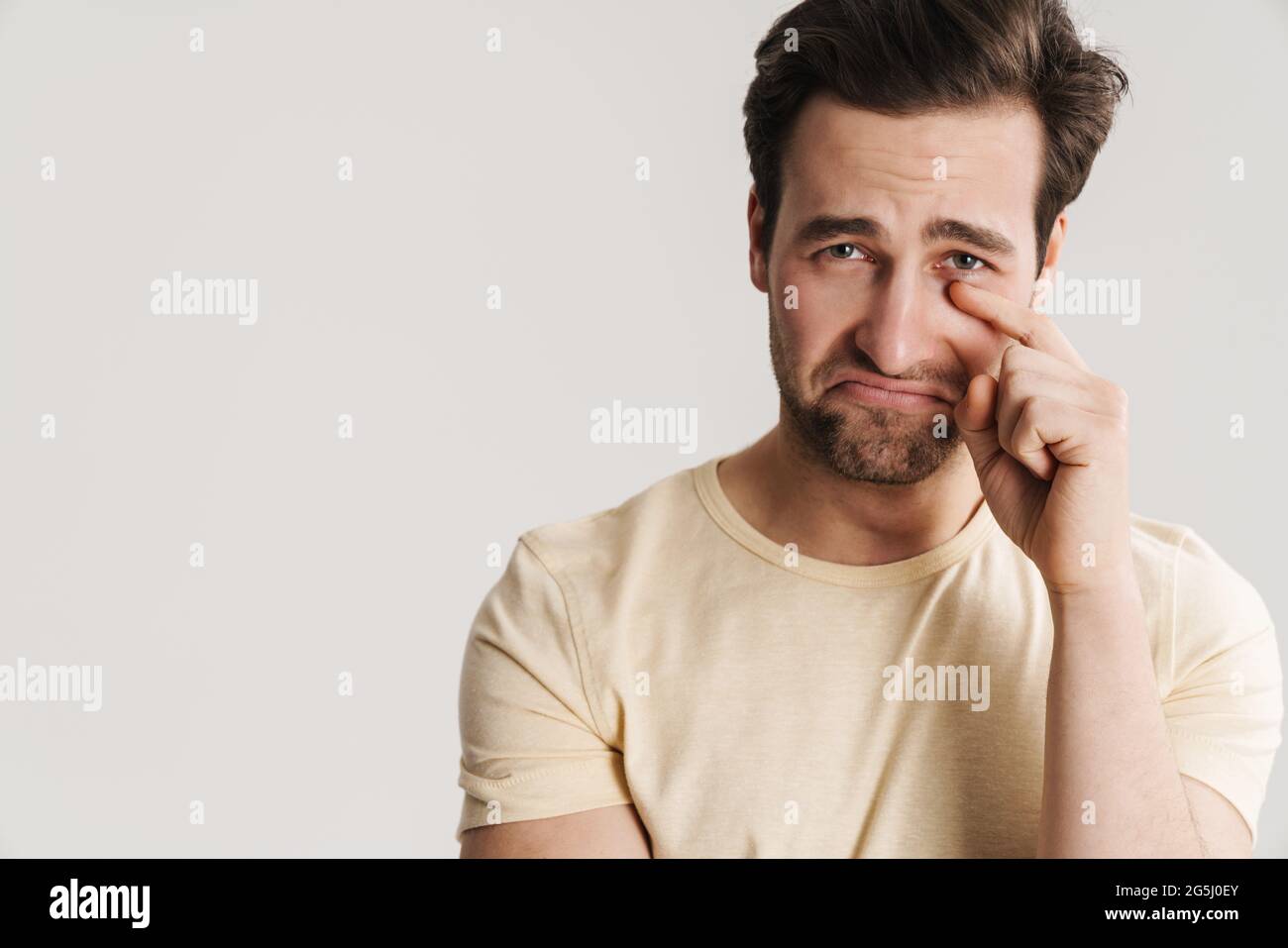 Unhappy handsome guy crying and looking at camera isolated over white ...