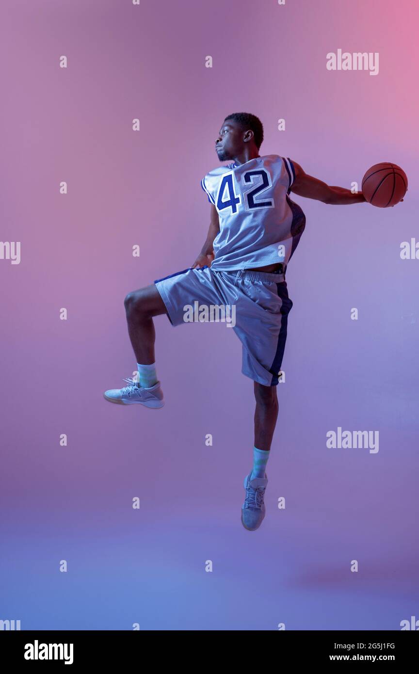 Basketball player jumping with ball in studio Stock Photo - Alamy