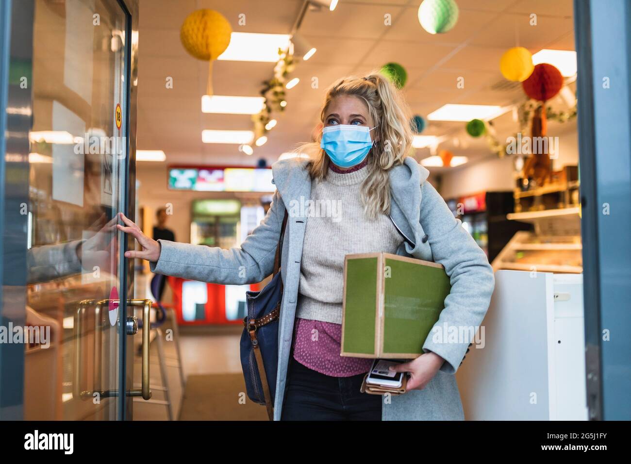Female customer carrying package while leaving store during COVID-19 ...