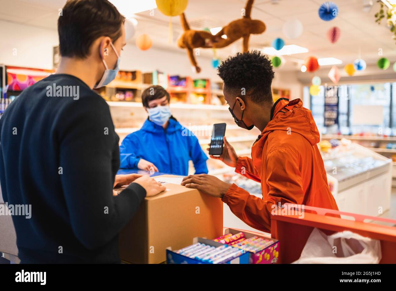 Male delivery person showing smart phone to entrepreneur at checkout in ...