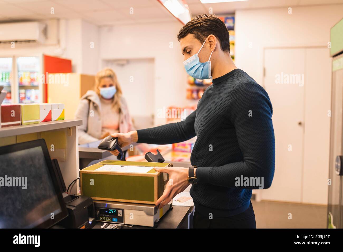 Male entrepreneur using bar code reader on package while female ...