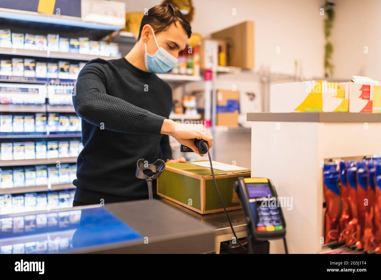 Male owner using bar code reader over package while standing at ...