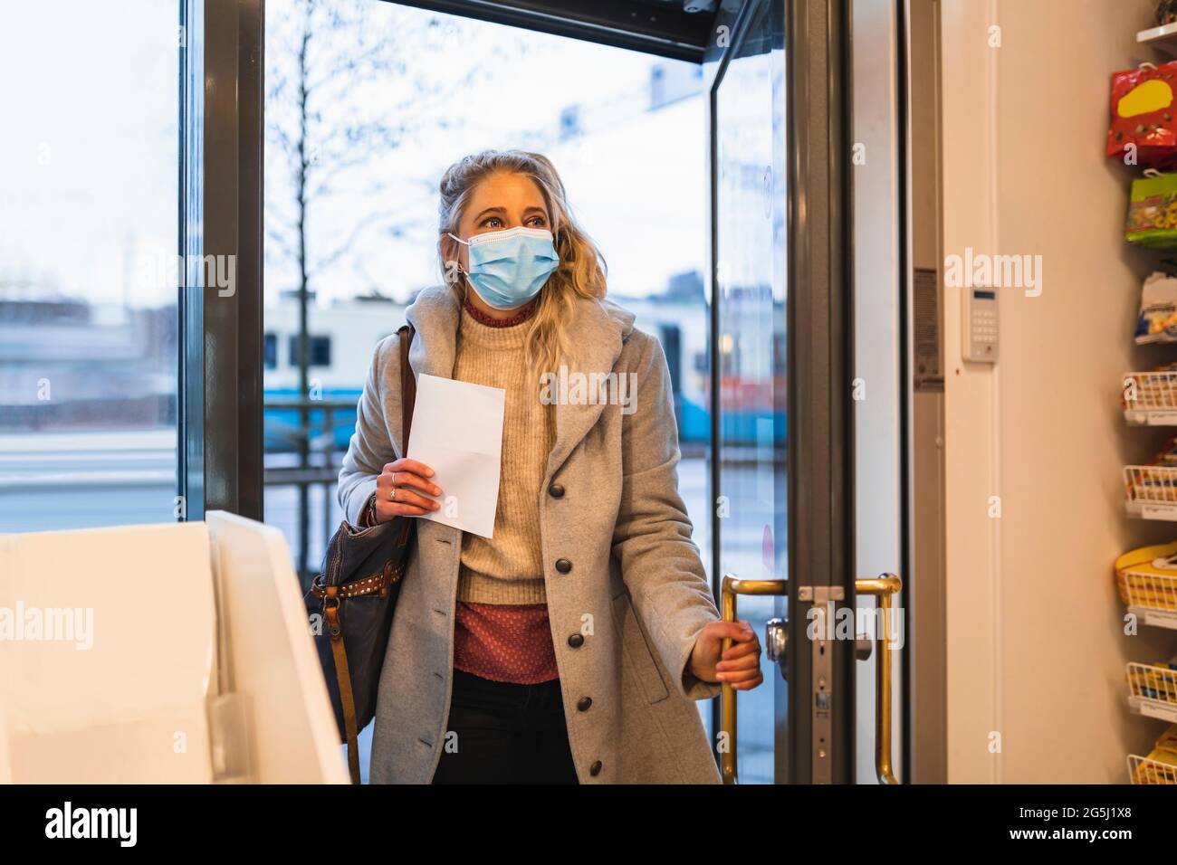 Mid adult female customer entering retail store during COVID-19 Stock ...
