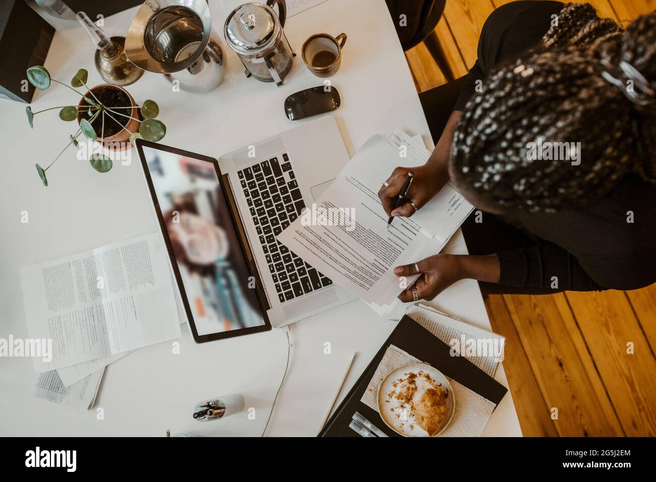 Female professional writing while attending video call with colleague ...