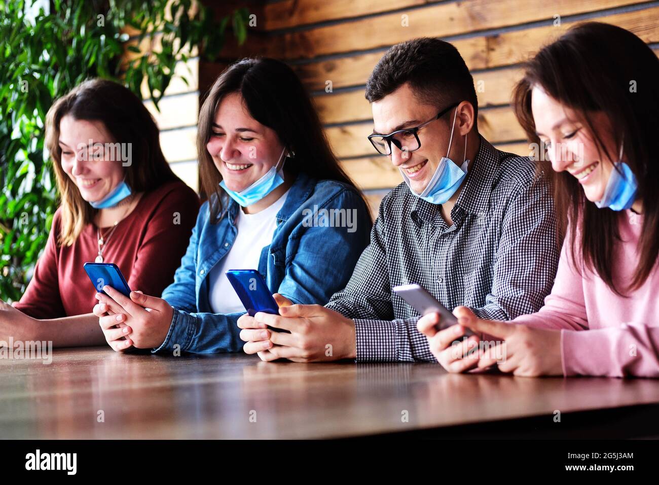 Millennials have fun with mobile phones - Young people with masks on ...