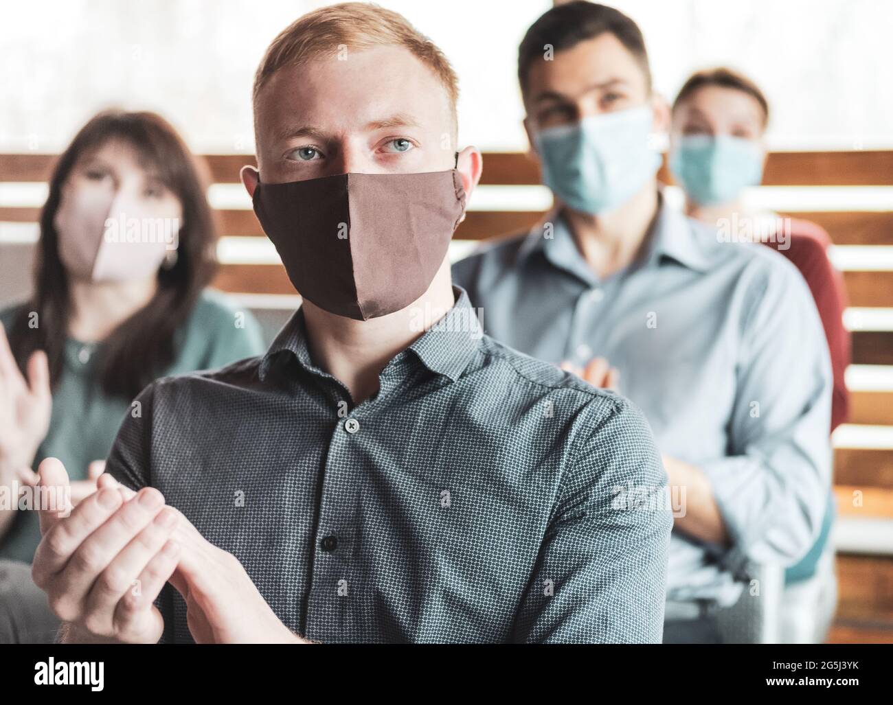 Group of young successful people wearing masks on their faces sitting ...