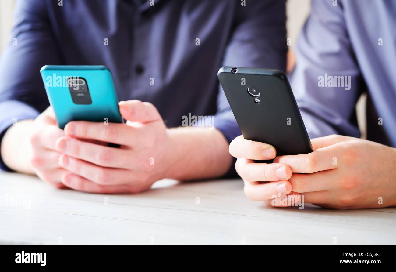 Two friends side by side use phones to type text messages - Hands and ...