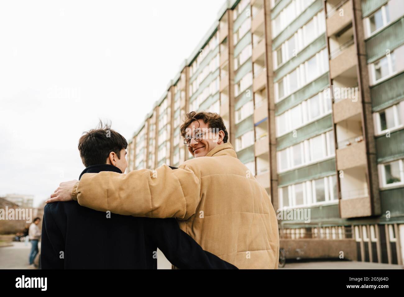 Smiling man looking over shoulder while walking with male friend Stock ...