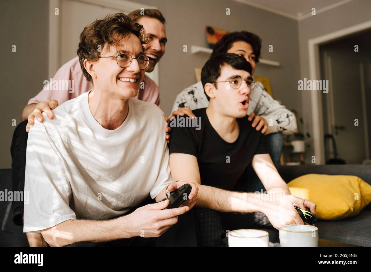 Happy male friends playing video game at home Stock Photo - Alamy