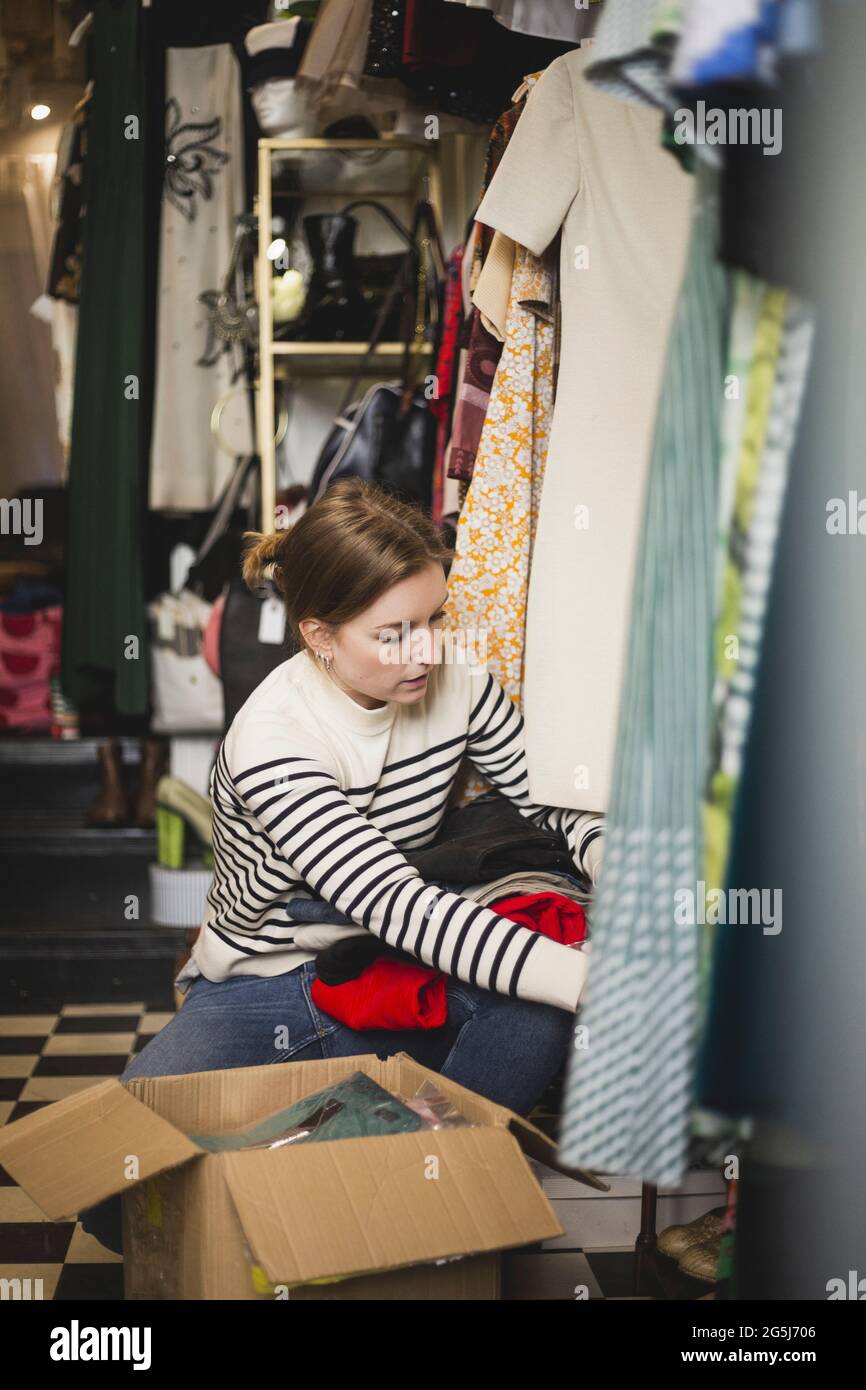 Caucasian female owner arranging clothes in rack at store Stock Photo ...