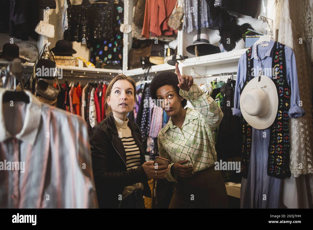 African female owner pointing while standing by customer in clothing ...