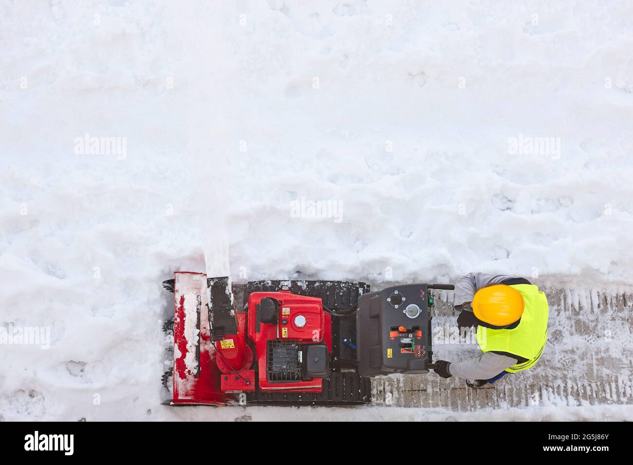 Worker cleaning snow on the sidewalk with a snowblower. Maintenance ...