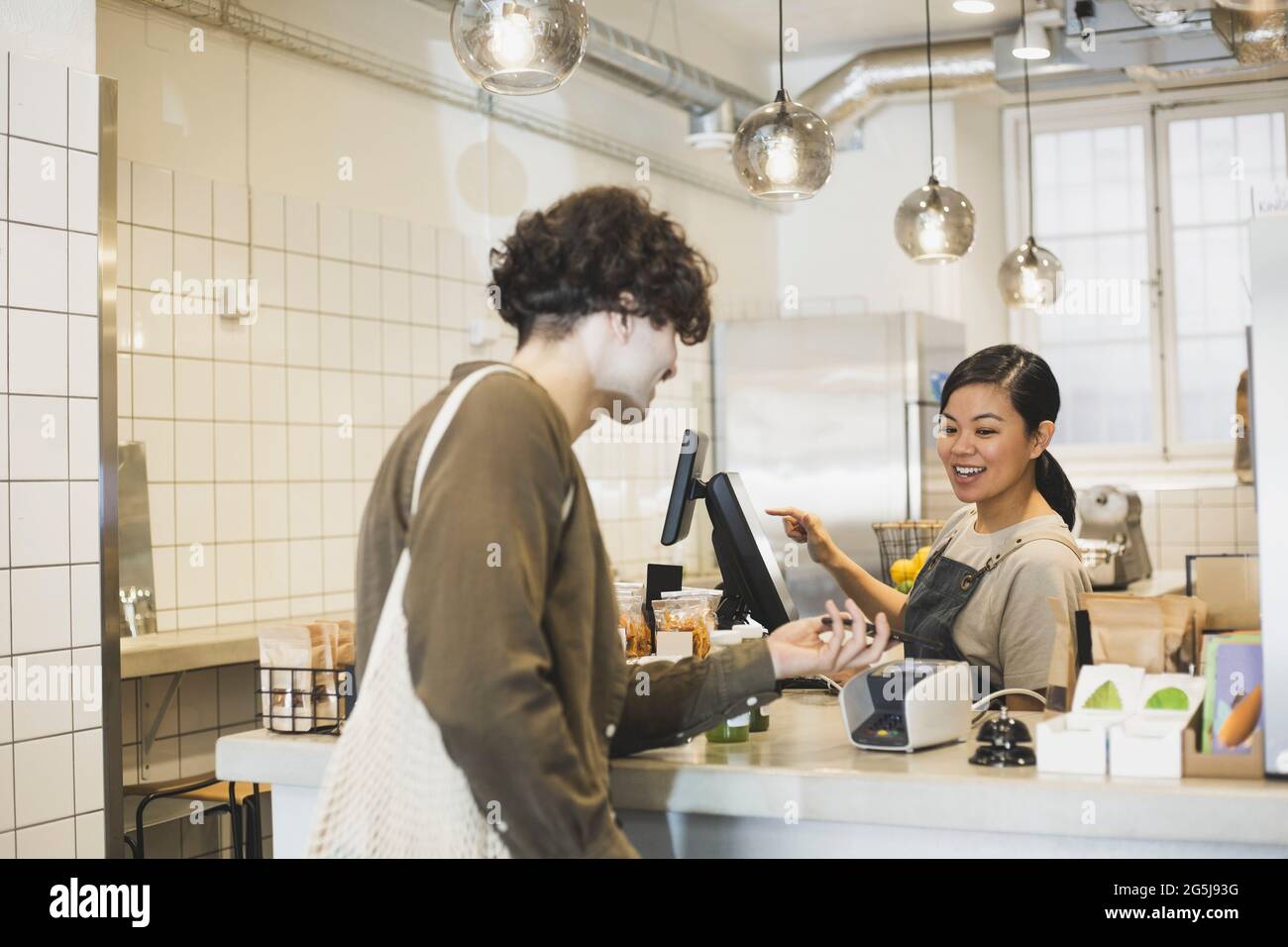Happy male customer doing contactless payment through smart phone to ...