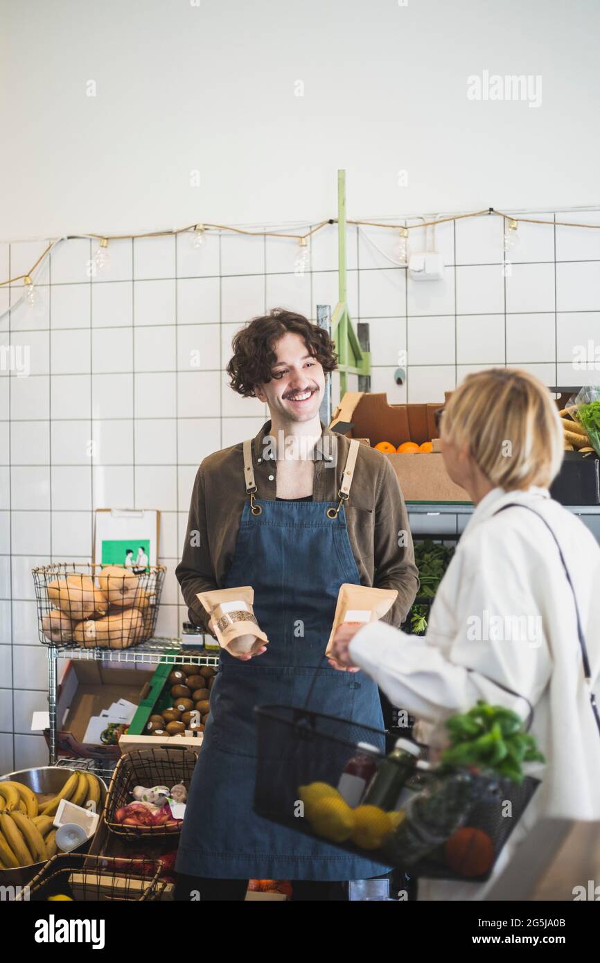 Smiling male owner talking with female customer in store Stock Photo ...