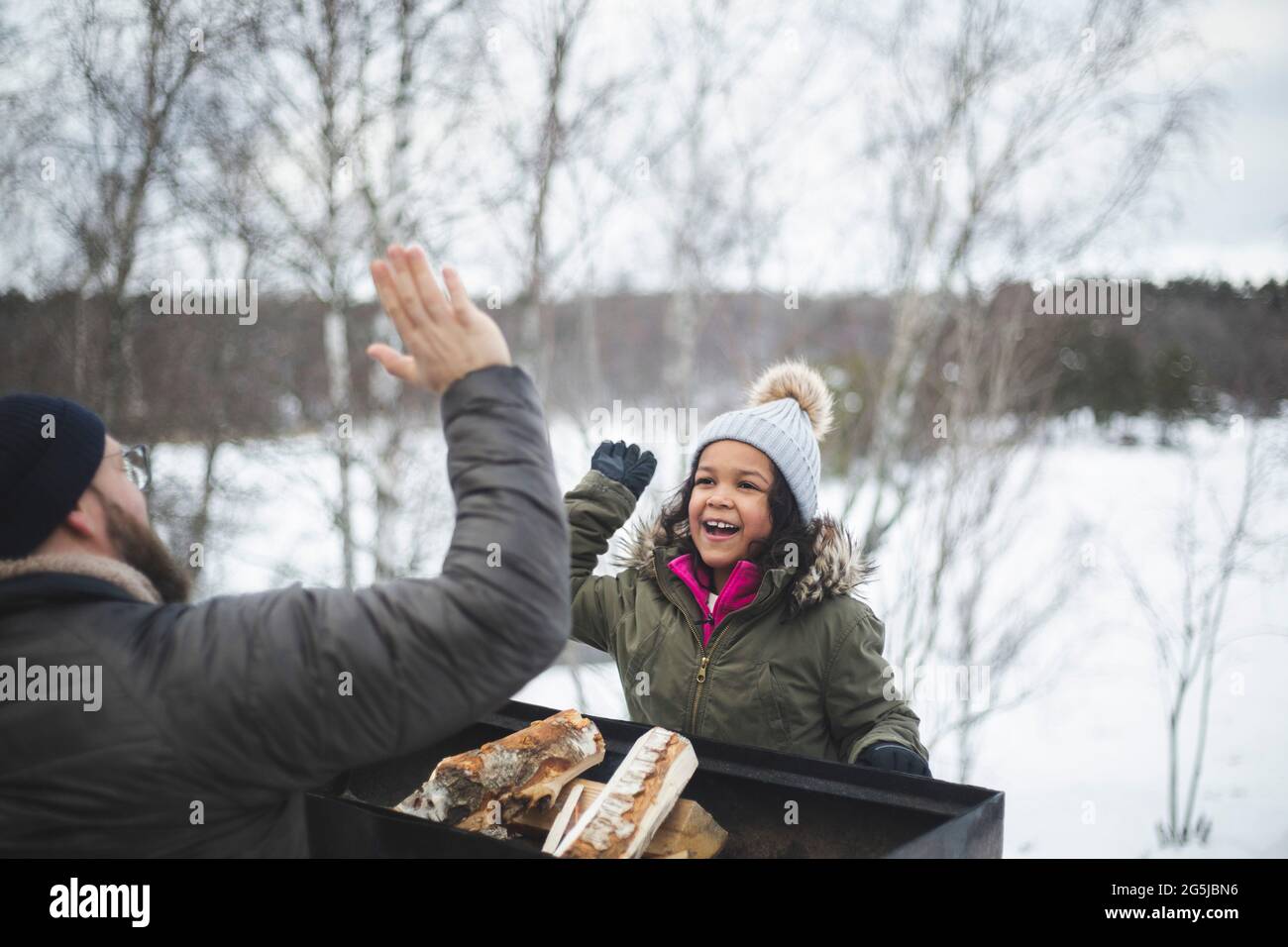 Happy girl giving high five to father during winter Stock Photo - Alamy