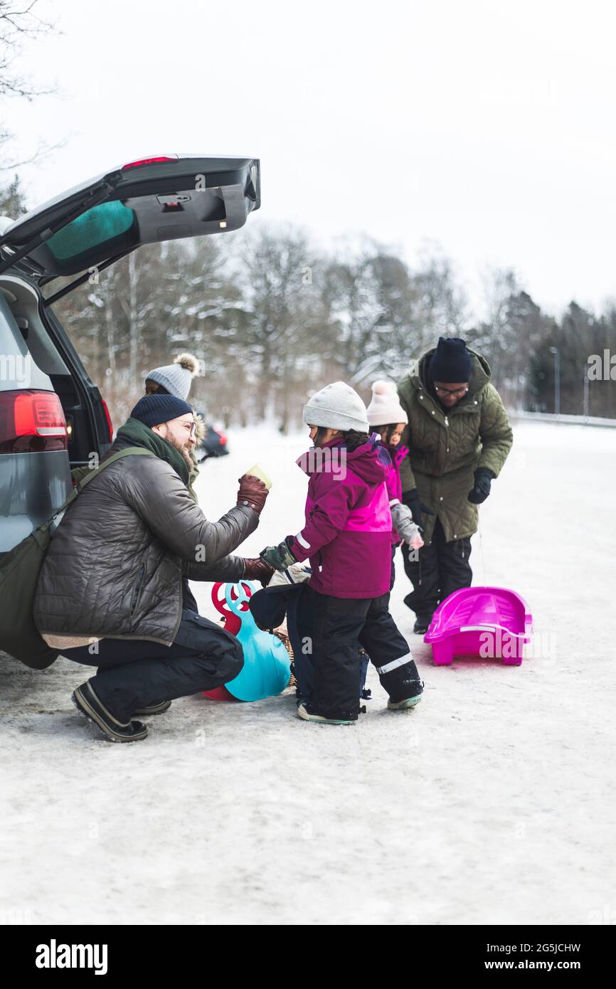 Father talking with daughter by family unloading car trunk during ...