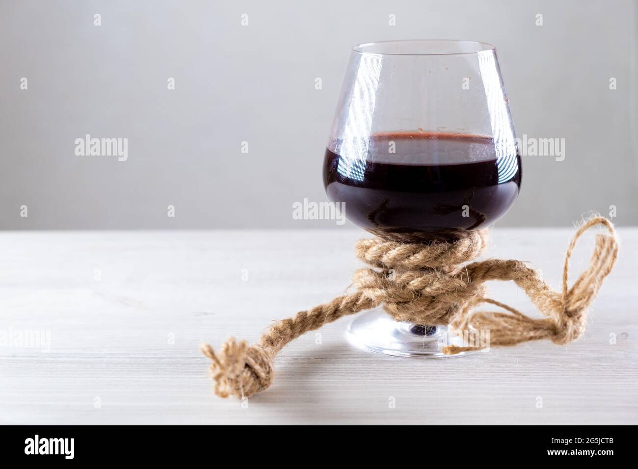 glass of red wine is tied with a rope. The concept of alcohol addiction ...