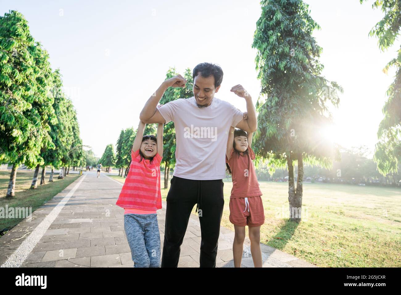strong dad with kids hanging on his arm while exercising Stock Photo ...