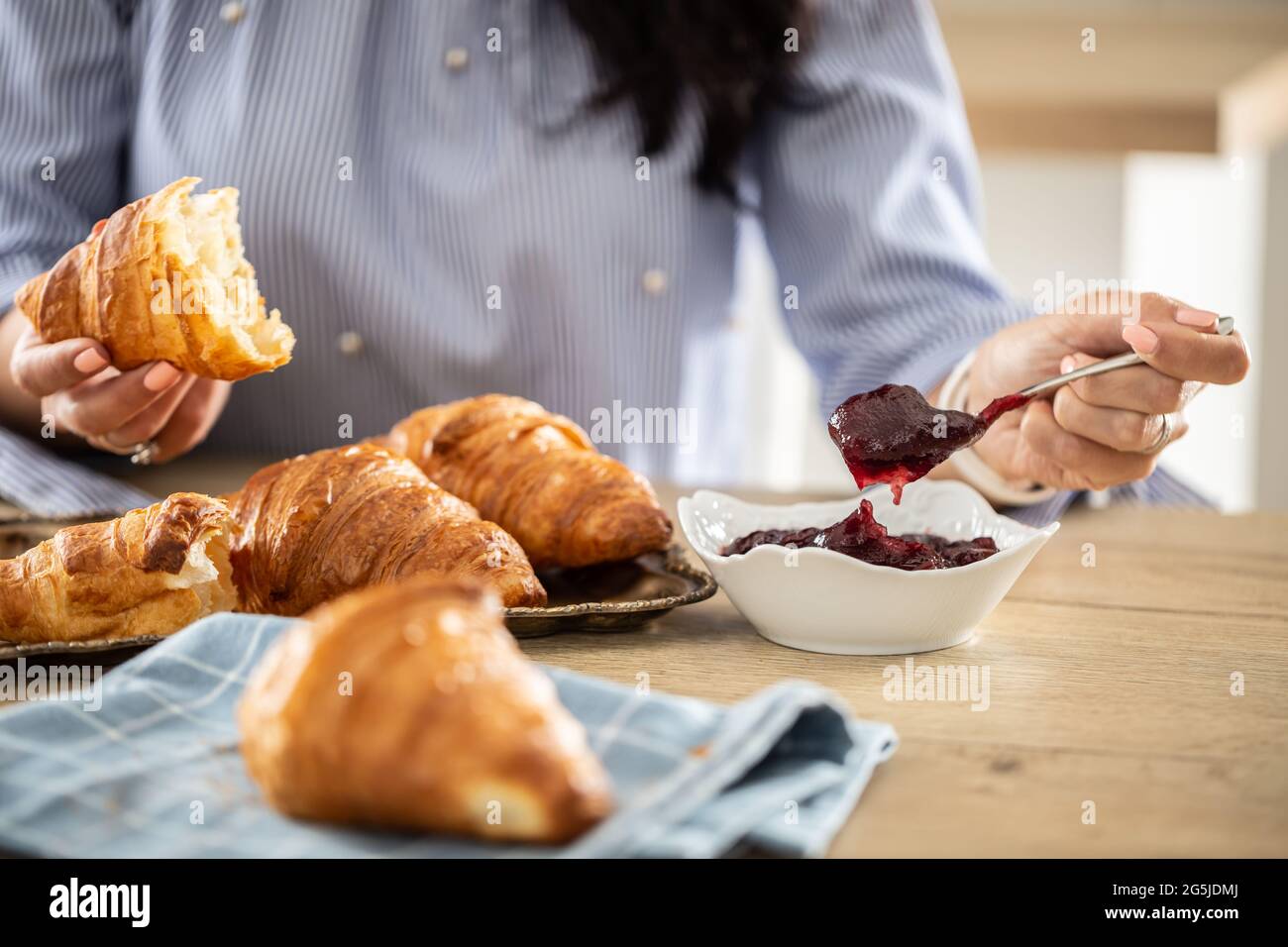 Woman's hand puts spoon of jam on a croissant having a breakfast Stock ...