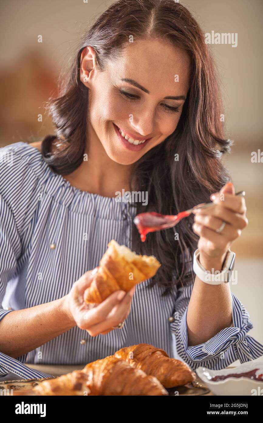 Woman smiles as she enjoys breakfast with croissant and jam Stock Photo ...