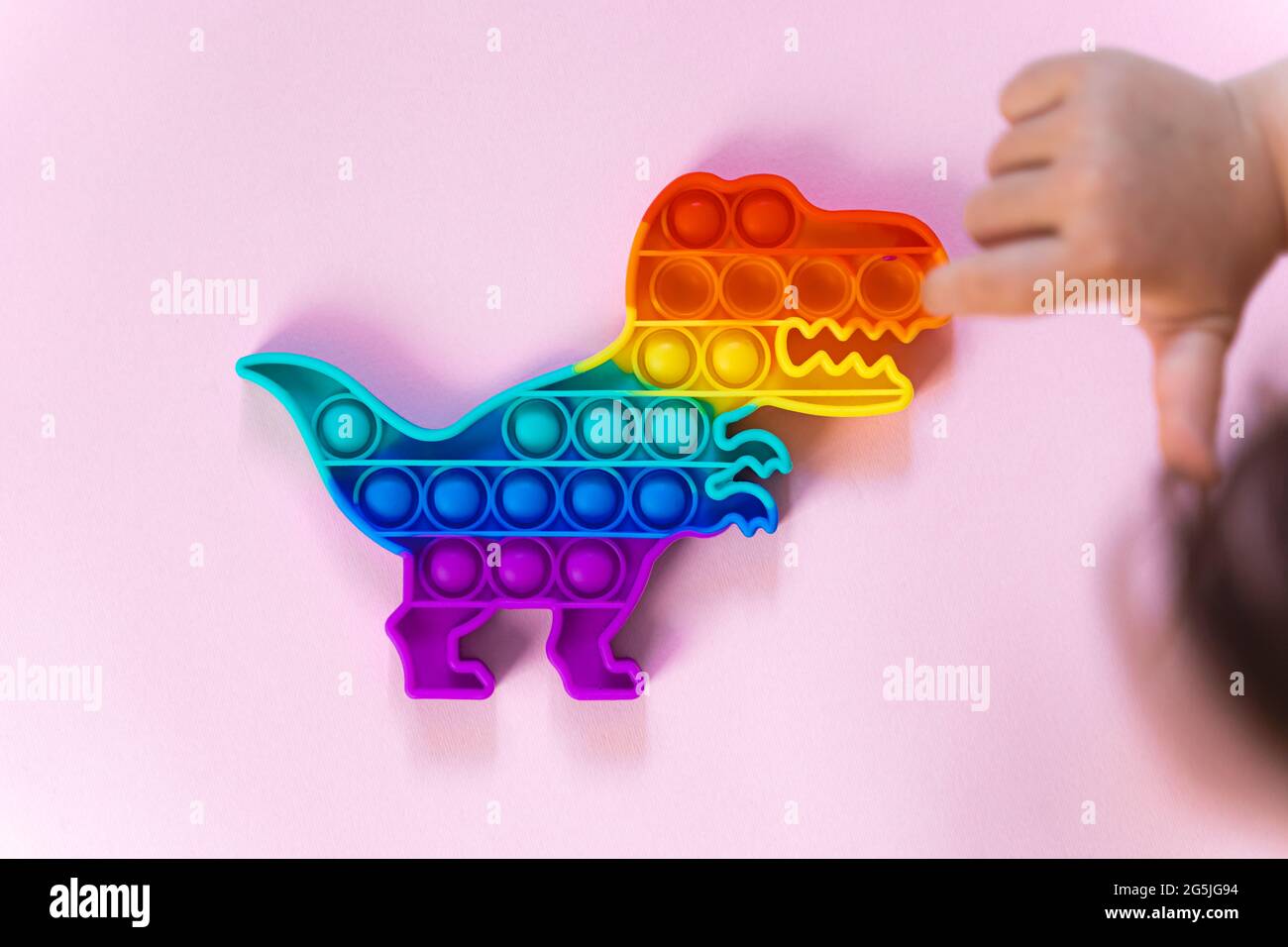 Popit rainbow toy in rainbow colours and dino shape. Trendy bubble pop ...