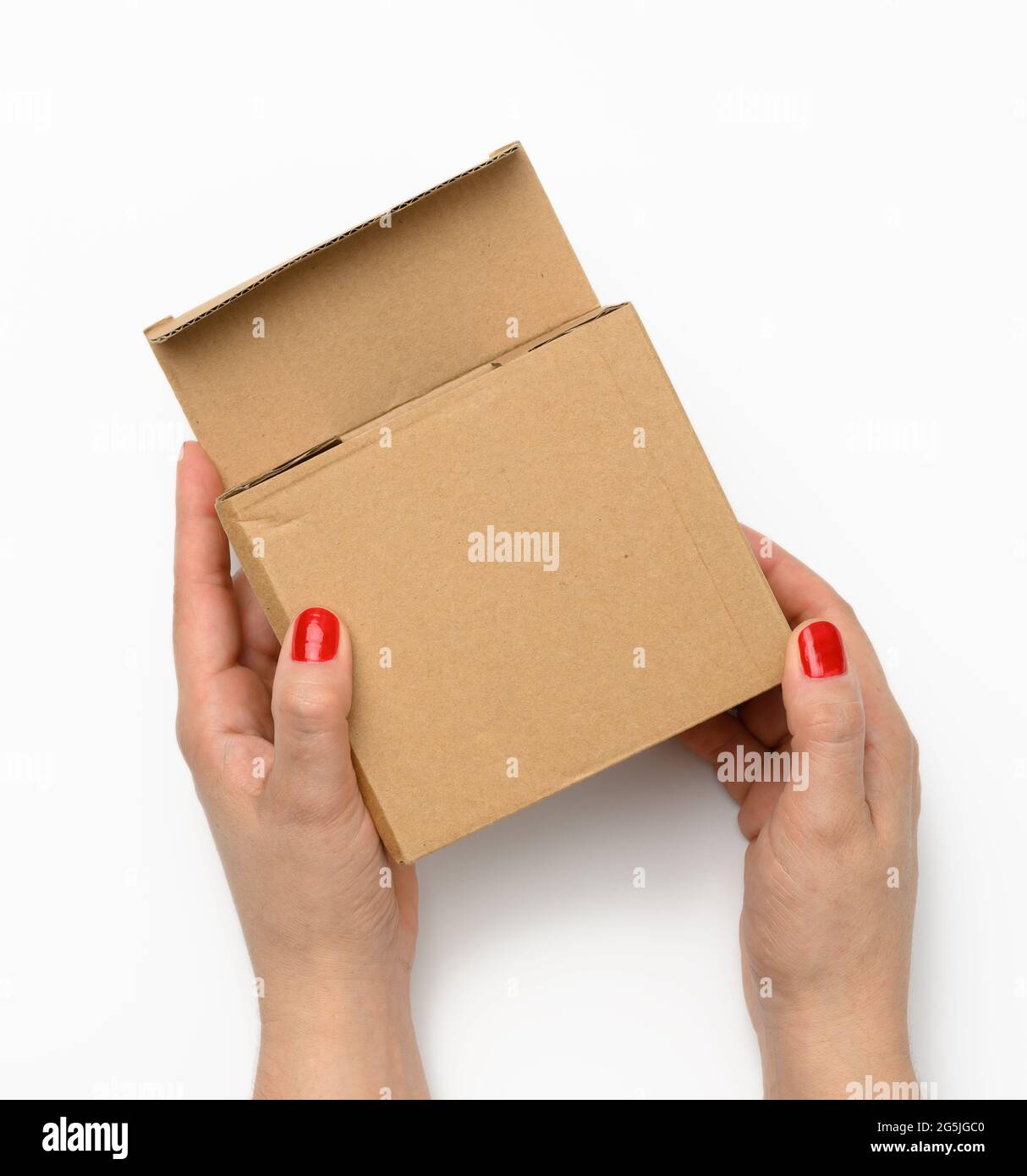 two female hands hold a square box made of brown corrugated cardboard ...