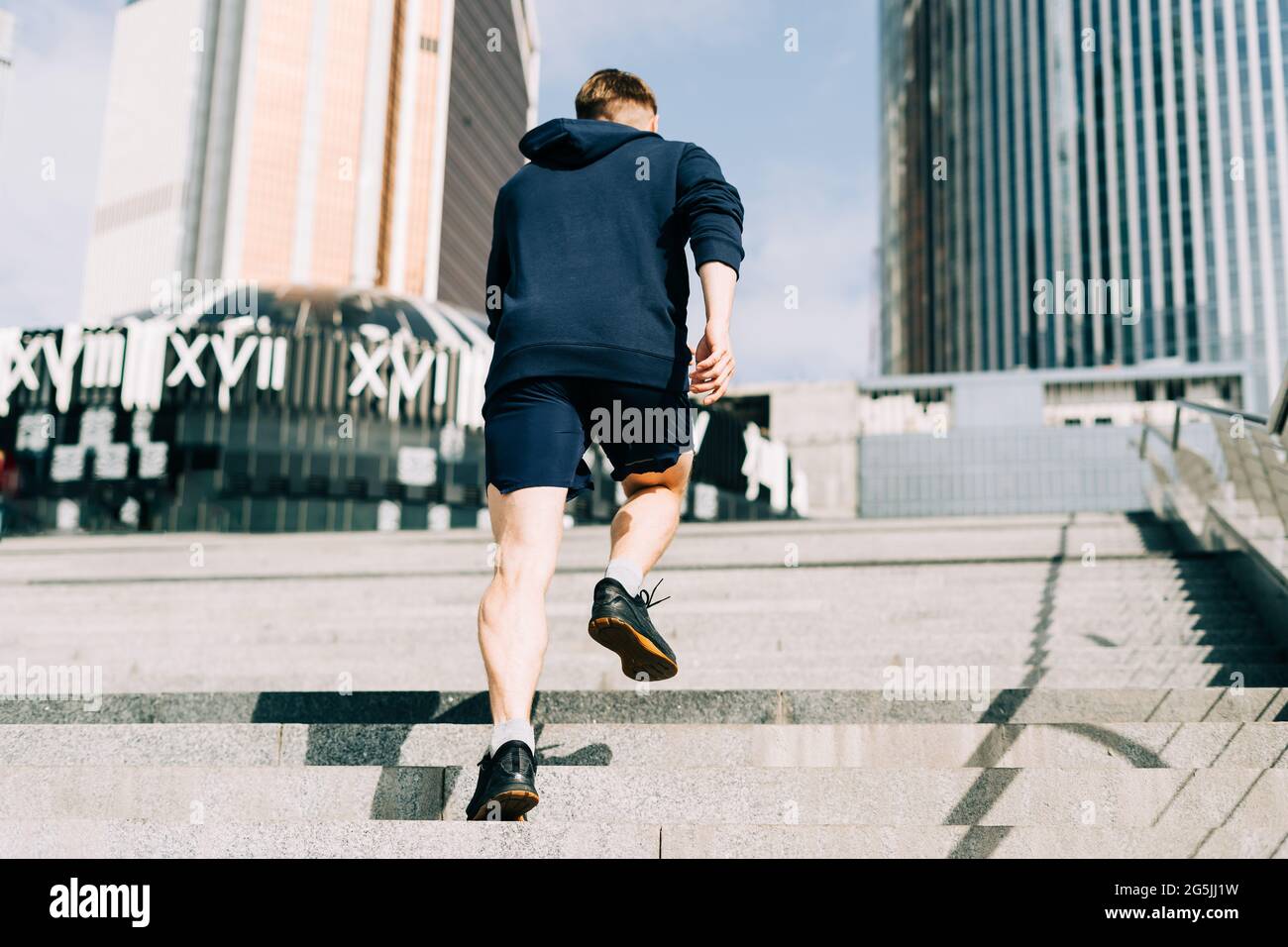 Young athlete man runner running up stairs on city stairs in summer on ...