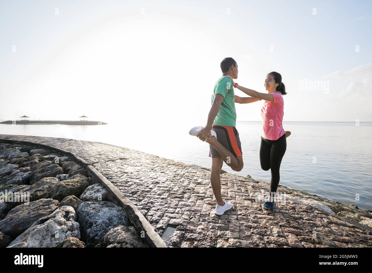 Athletic young couple doing stretching legs exercises together Stock ...