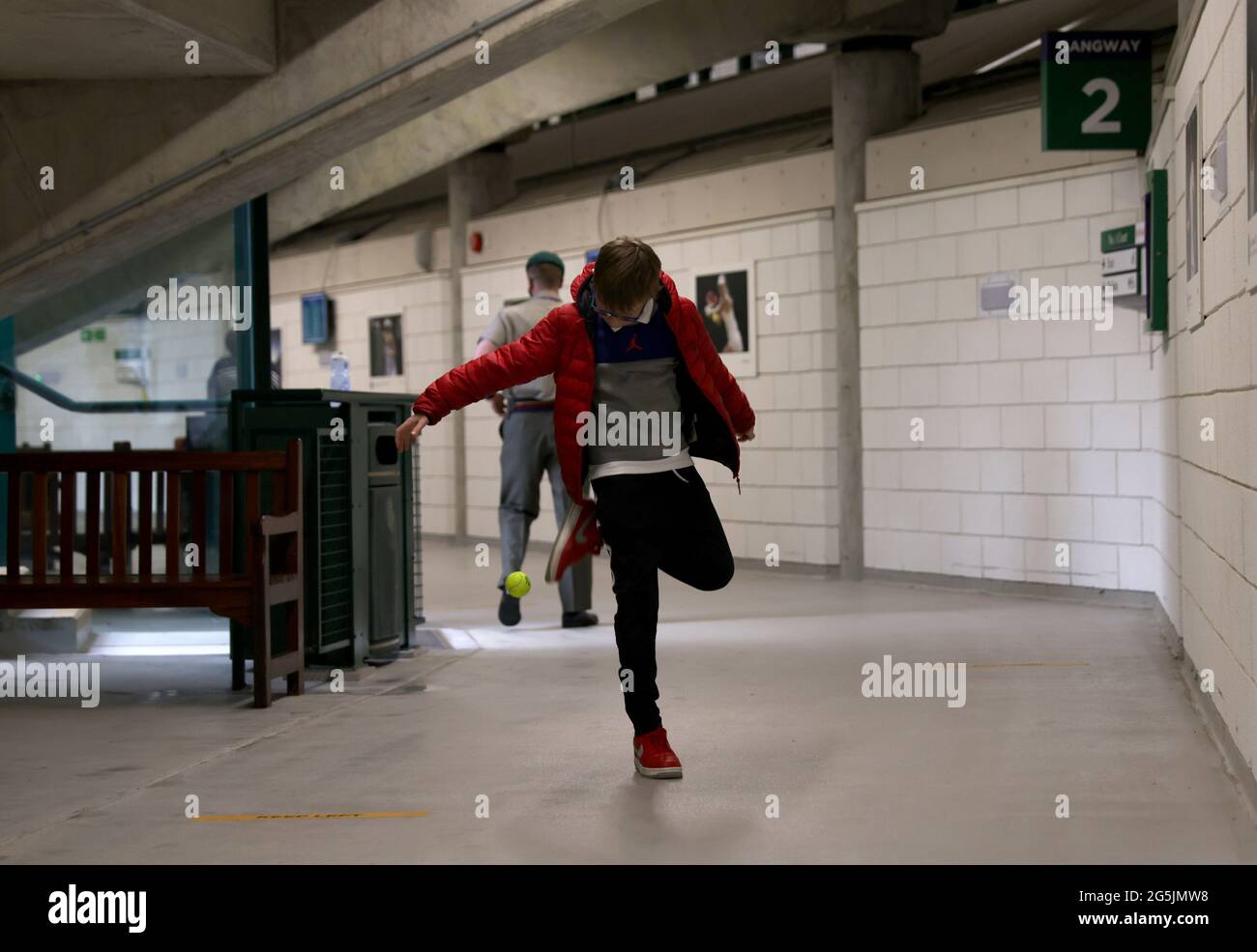 A spectator plays with a tennis ball in the concourse as they wait for ...