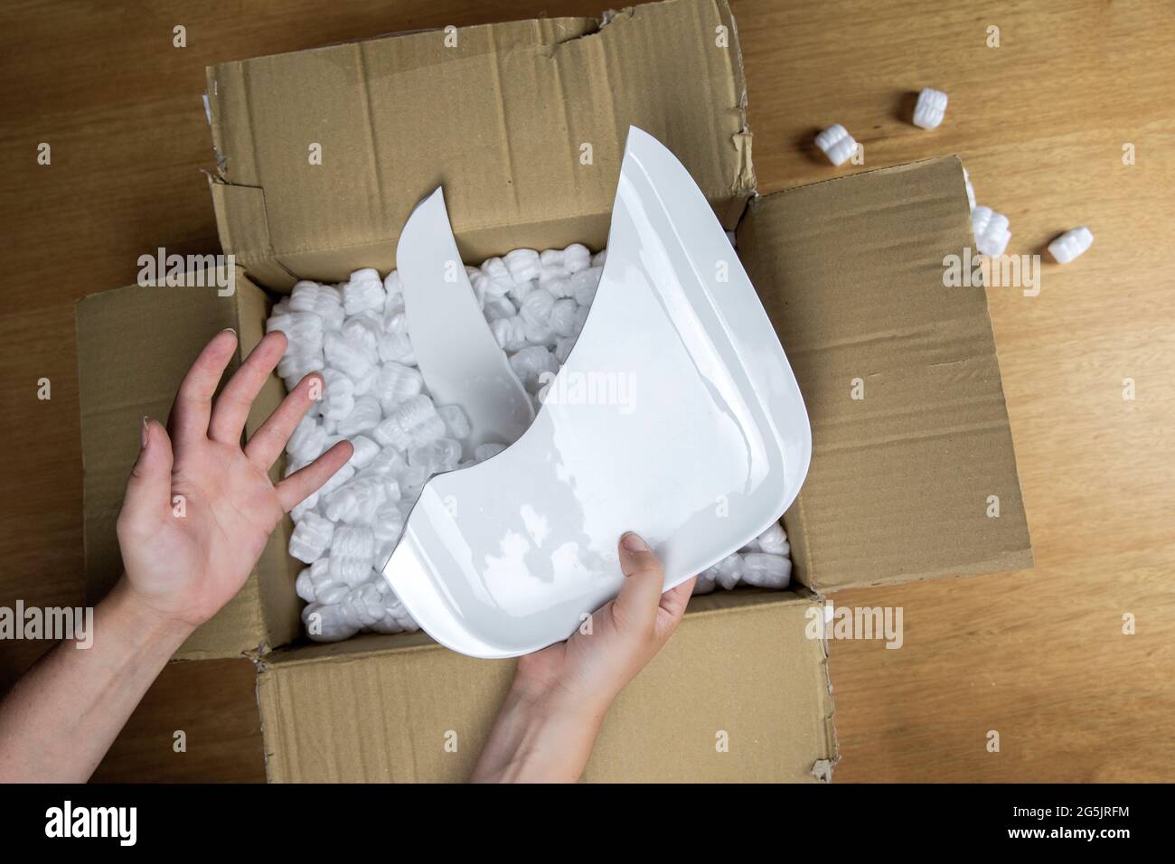 Broken plate in damaged cardboard box top view, damaged home delivery ...