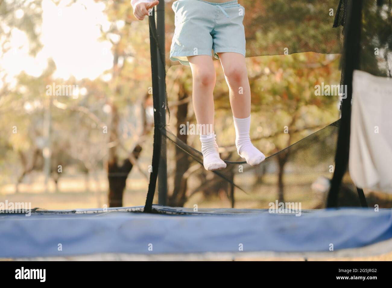 Closeup of a little boy jumping high on a trampoline; a shot without ...