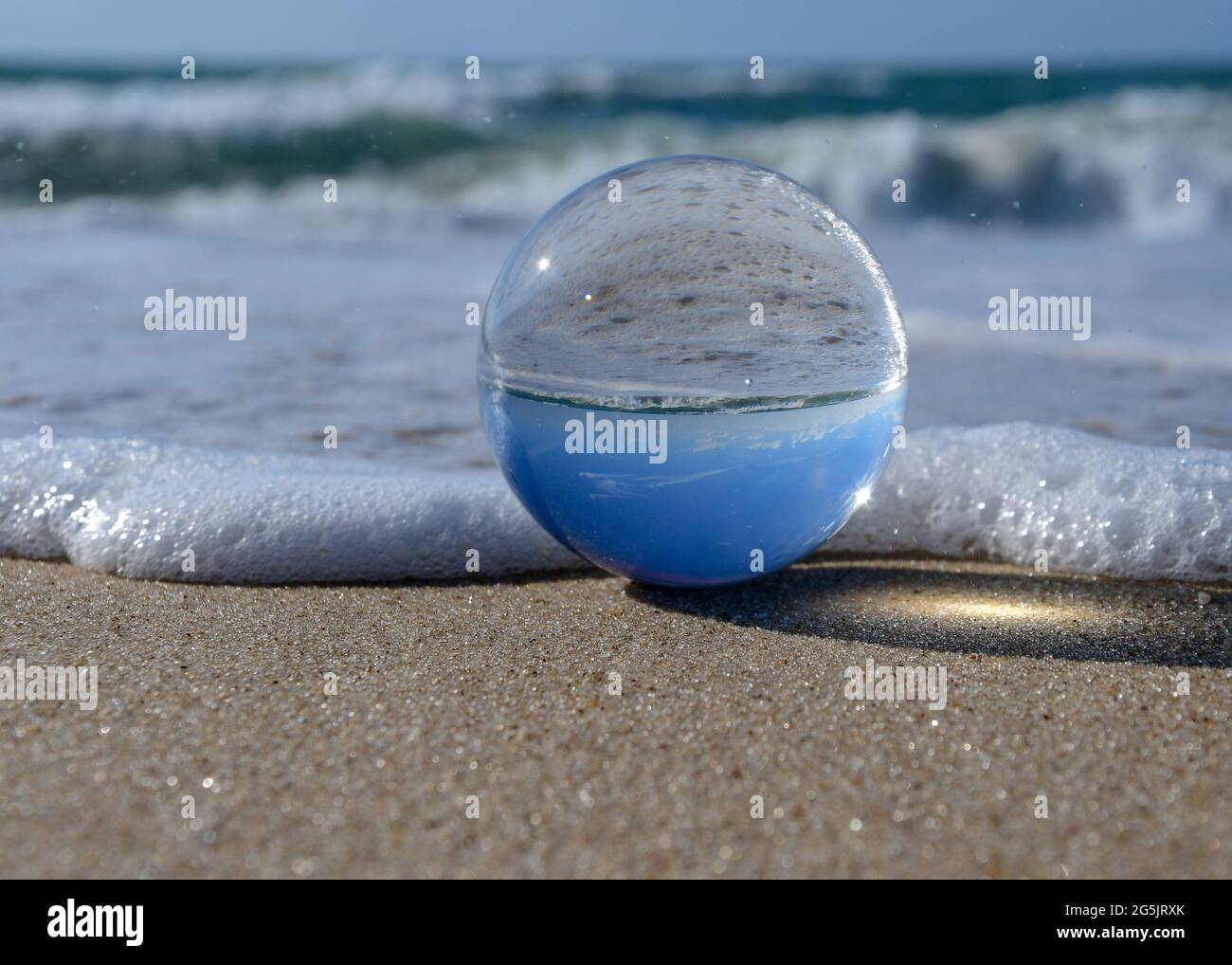 Crystal ball at a beach with the surroundings reflecting in the glass ...