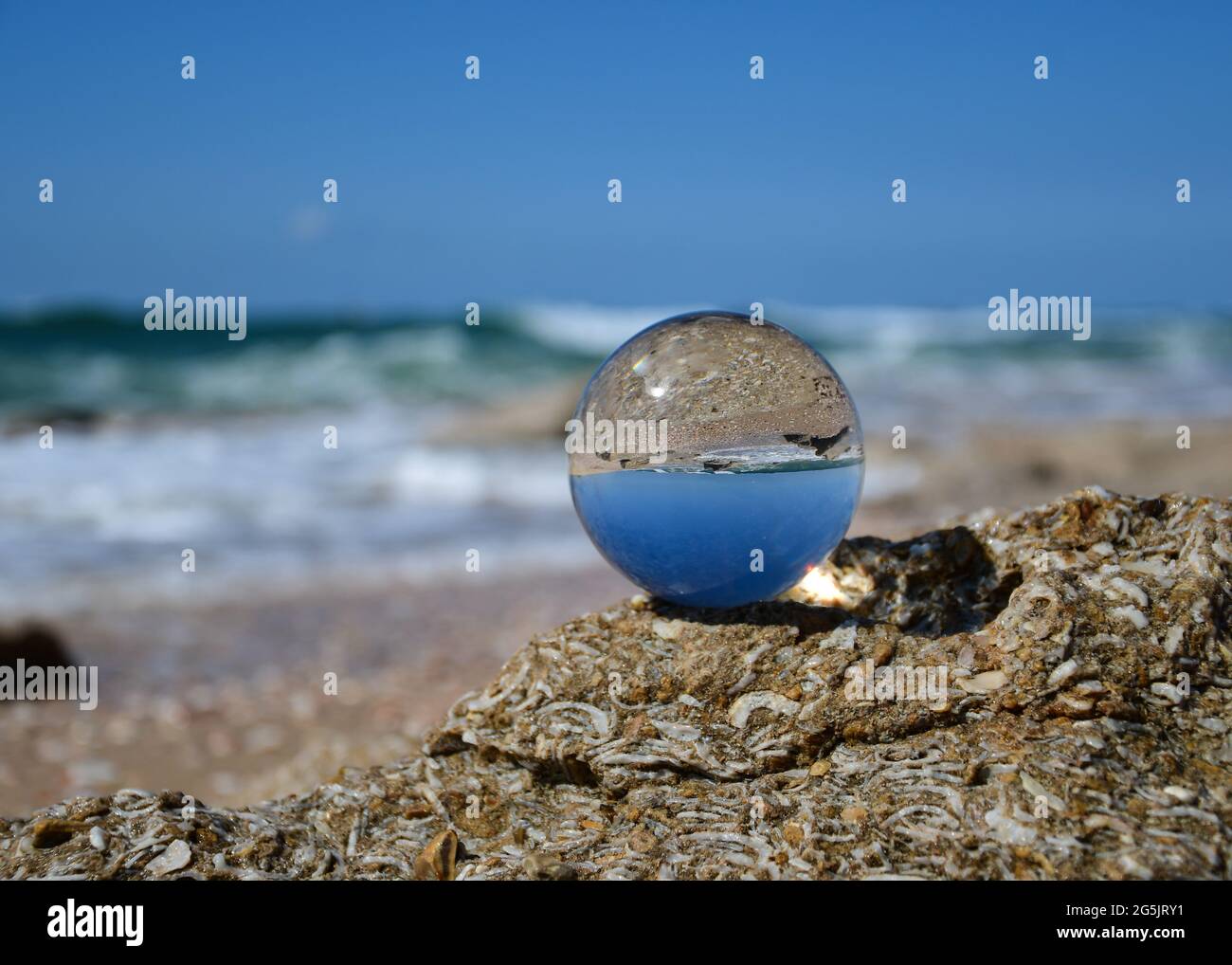 Crystal ball at a beach with the surroundings reflecting in the glass ...