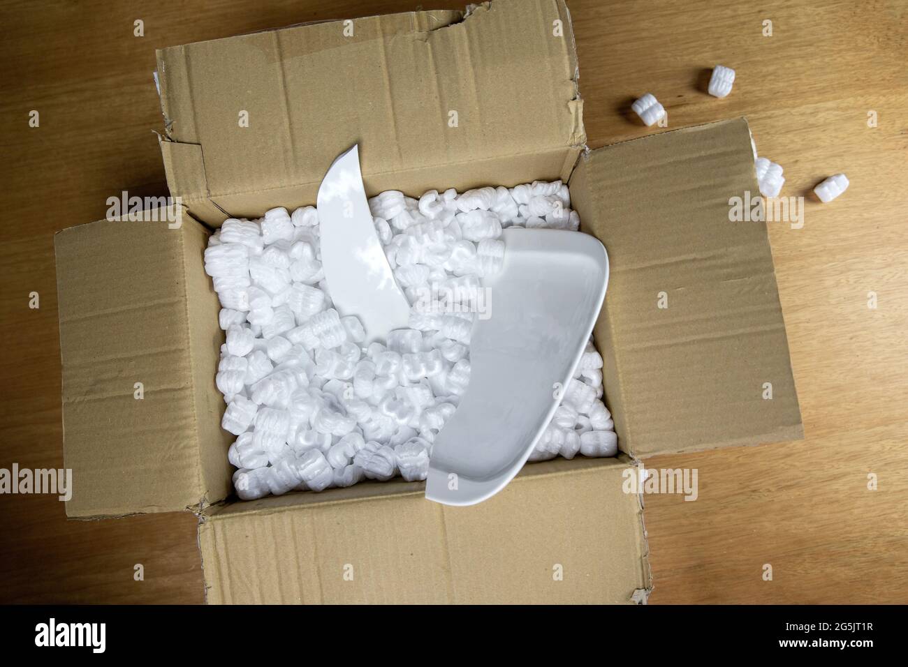 Broken plate in damaged cardboard box top view, damaged home delivery ...