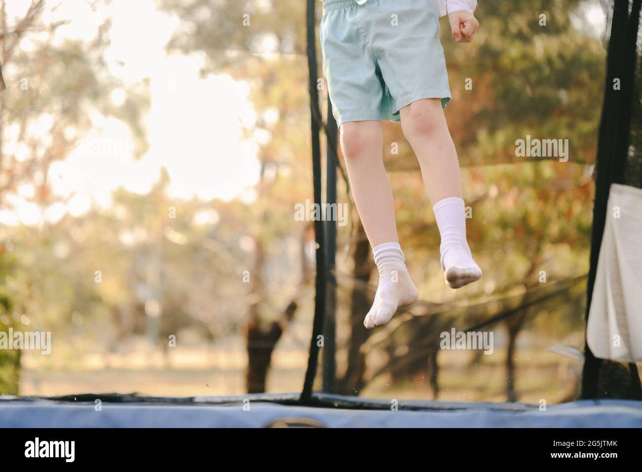 Legs of a little boy jumping high on a trampoline Stock Photo - Alamy