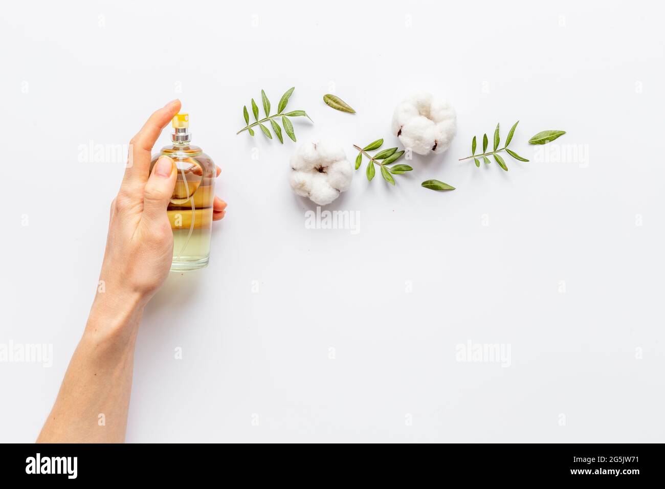 Female hand spray perfume bottle and flow of flowers Stock Photo - Alamy