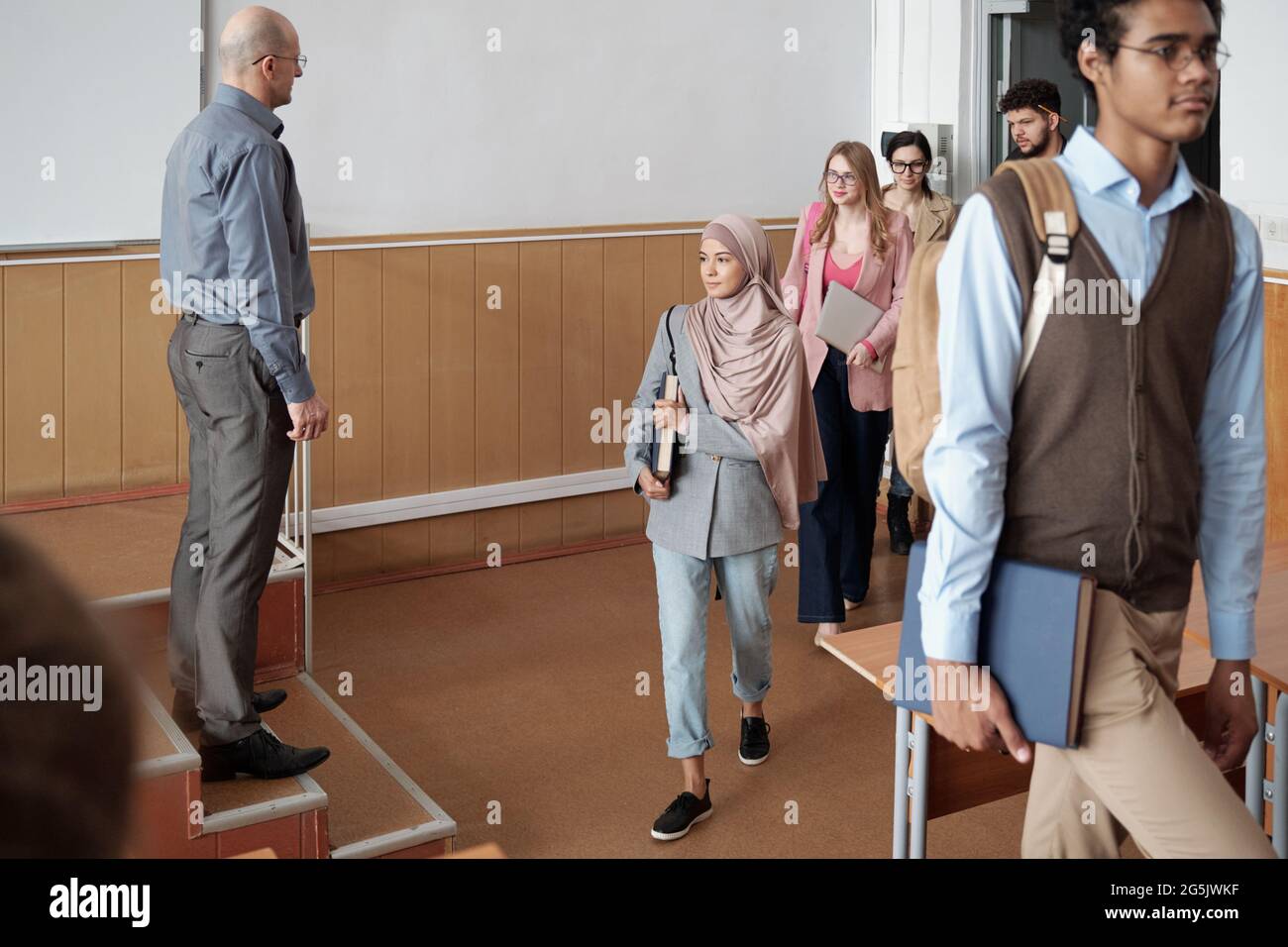 Group of intercultural students entering classroom before lesson Stock ...