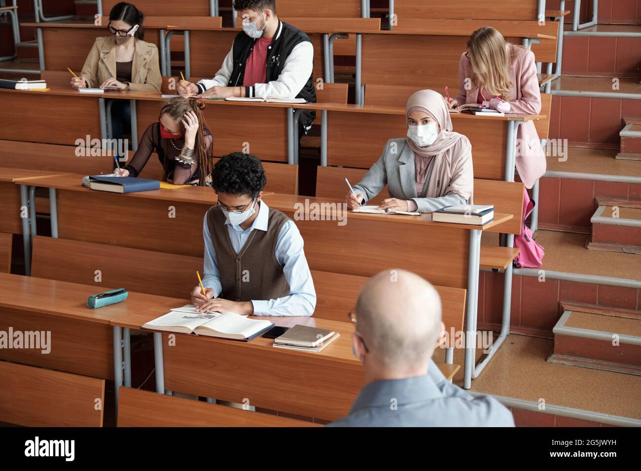Group of students making notes by desks at lecture Stock Photo - Alamy