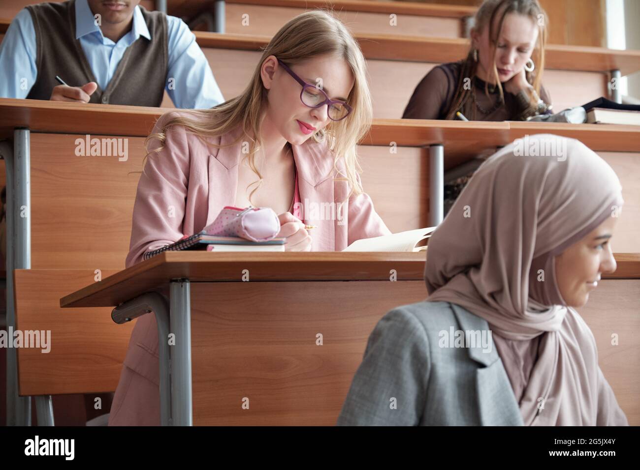 Several students sitting in rows and making notes at lesson Stock Photo ...
