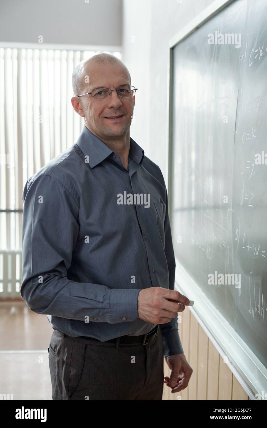 Happy professor standing by blackboard in front of camera Stock Photo ...