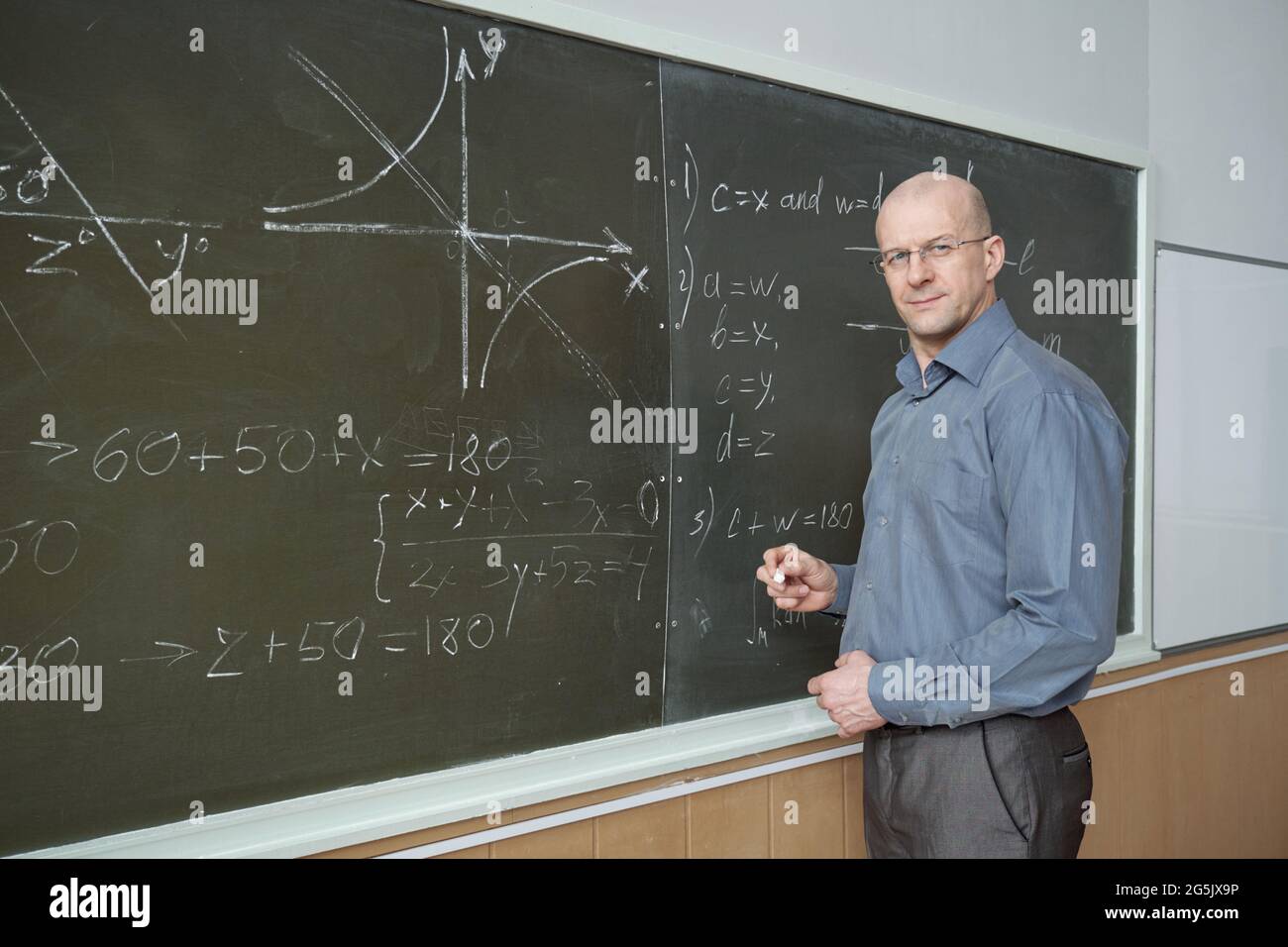 Serious professor explaining algebraic formula by blackboard Stock ...