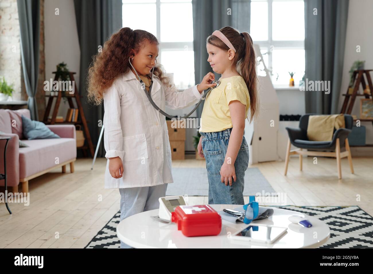 Two little girls playing doctors at home or kindergarten Stock Photo ...