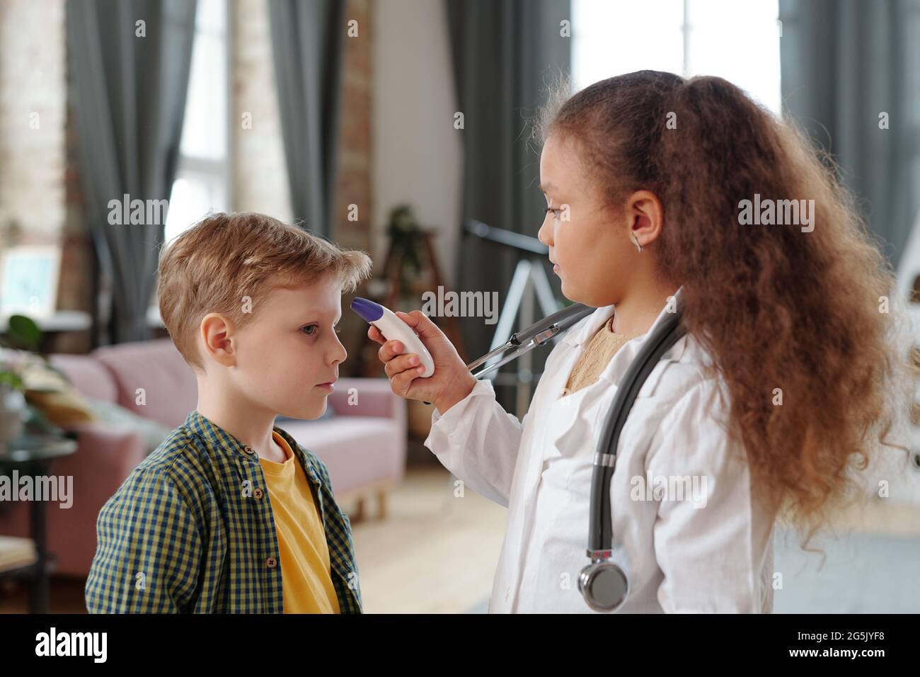 Little girl with thermometer measuring body temperature of boy Stock ...