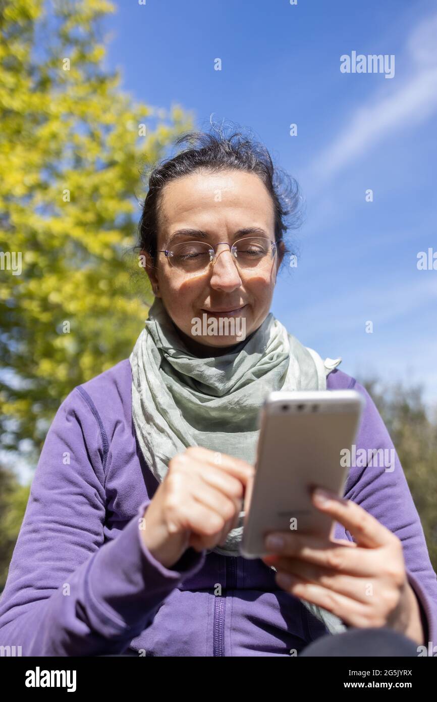 Pretty , young spanish woman in excursion in the forest, using mobile ...