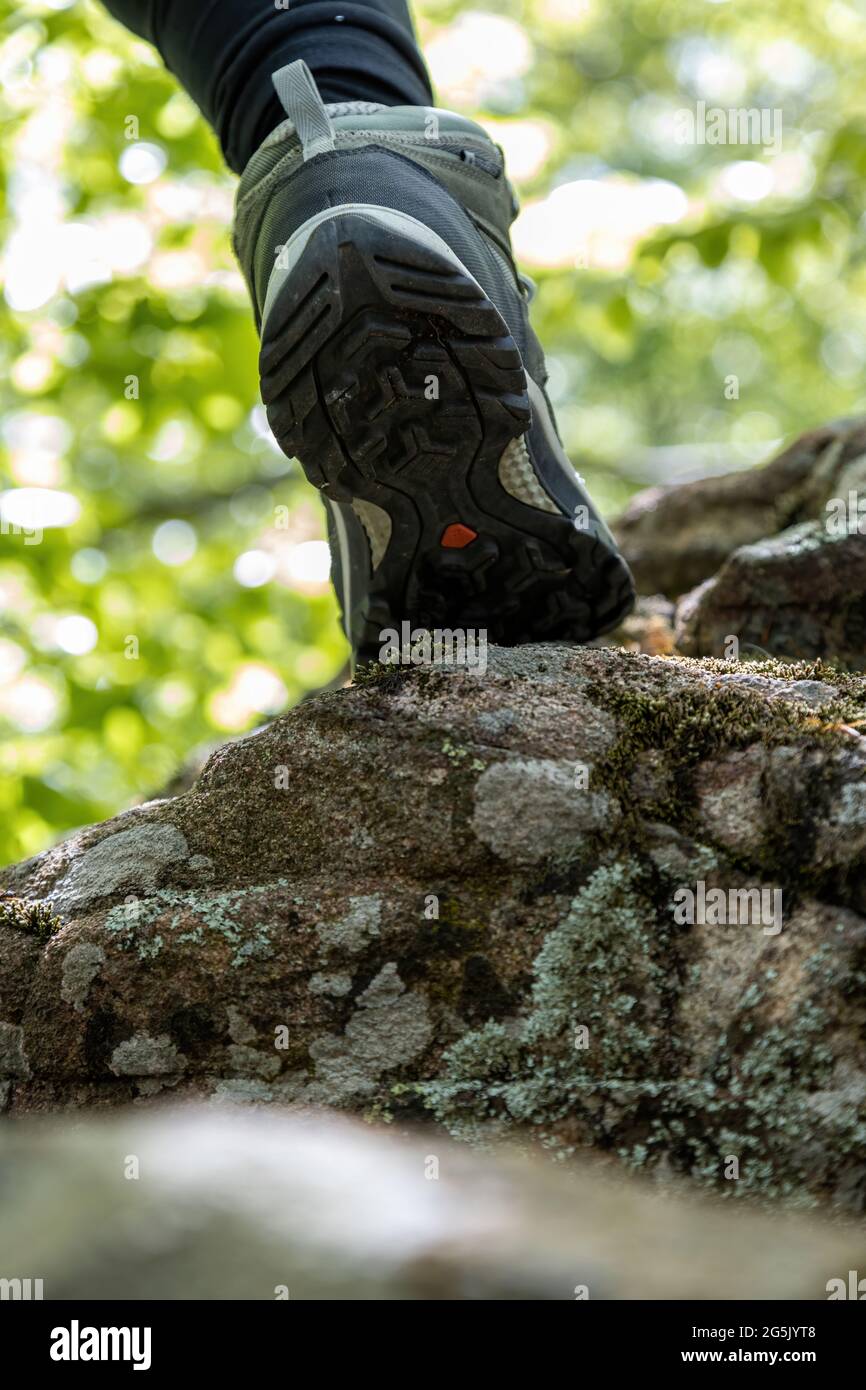 Boot of hiker on forest trail. Traveler feet are stepping on the rock ...